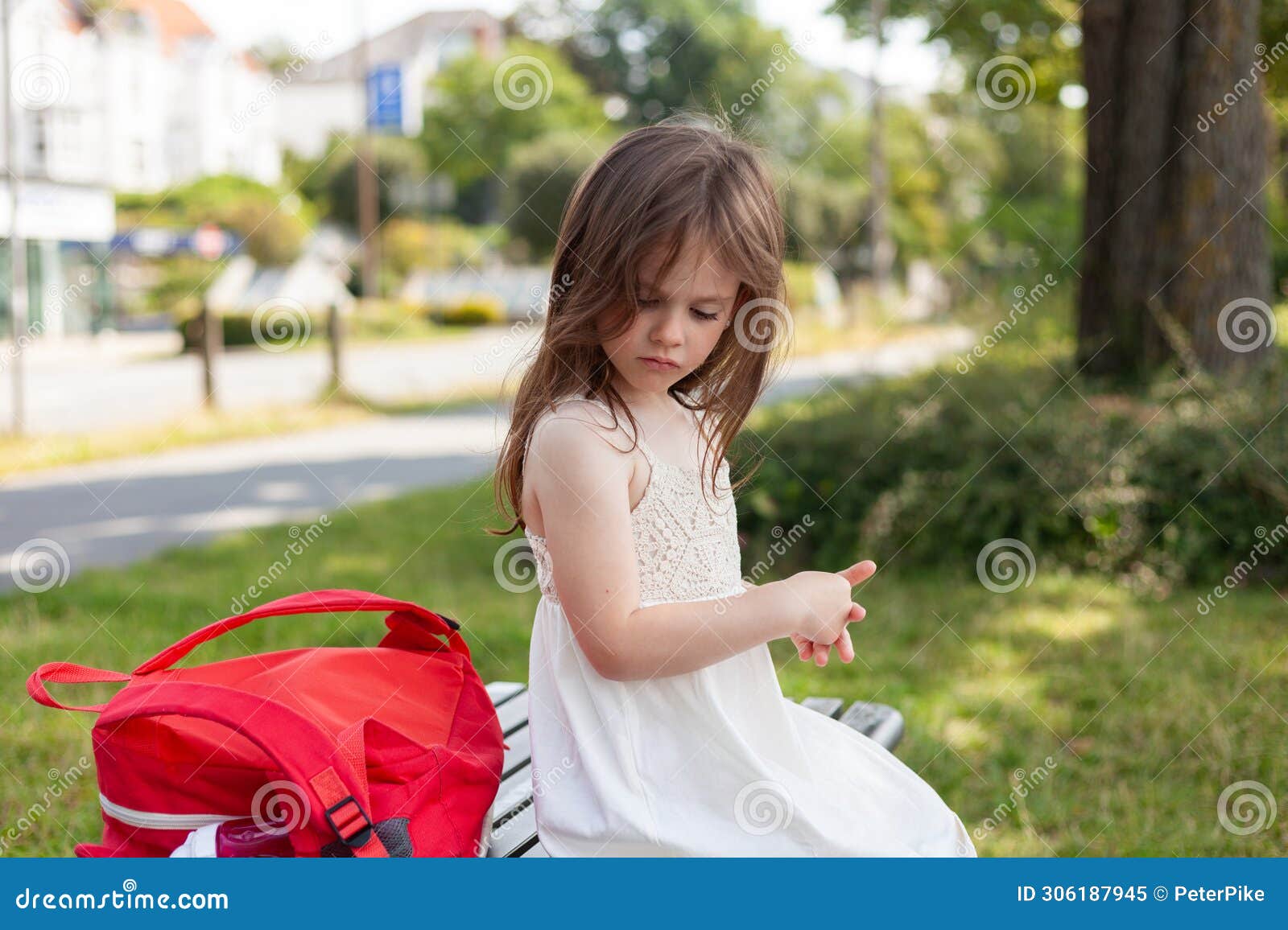 Cute Little Girl Sitting on a Bench in the Park with a Red Backpack ...