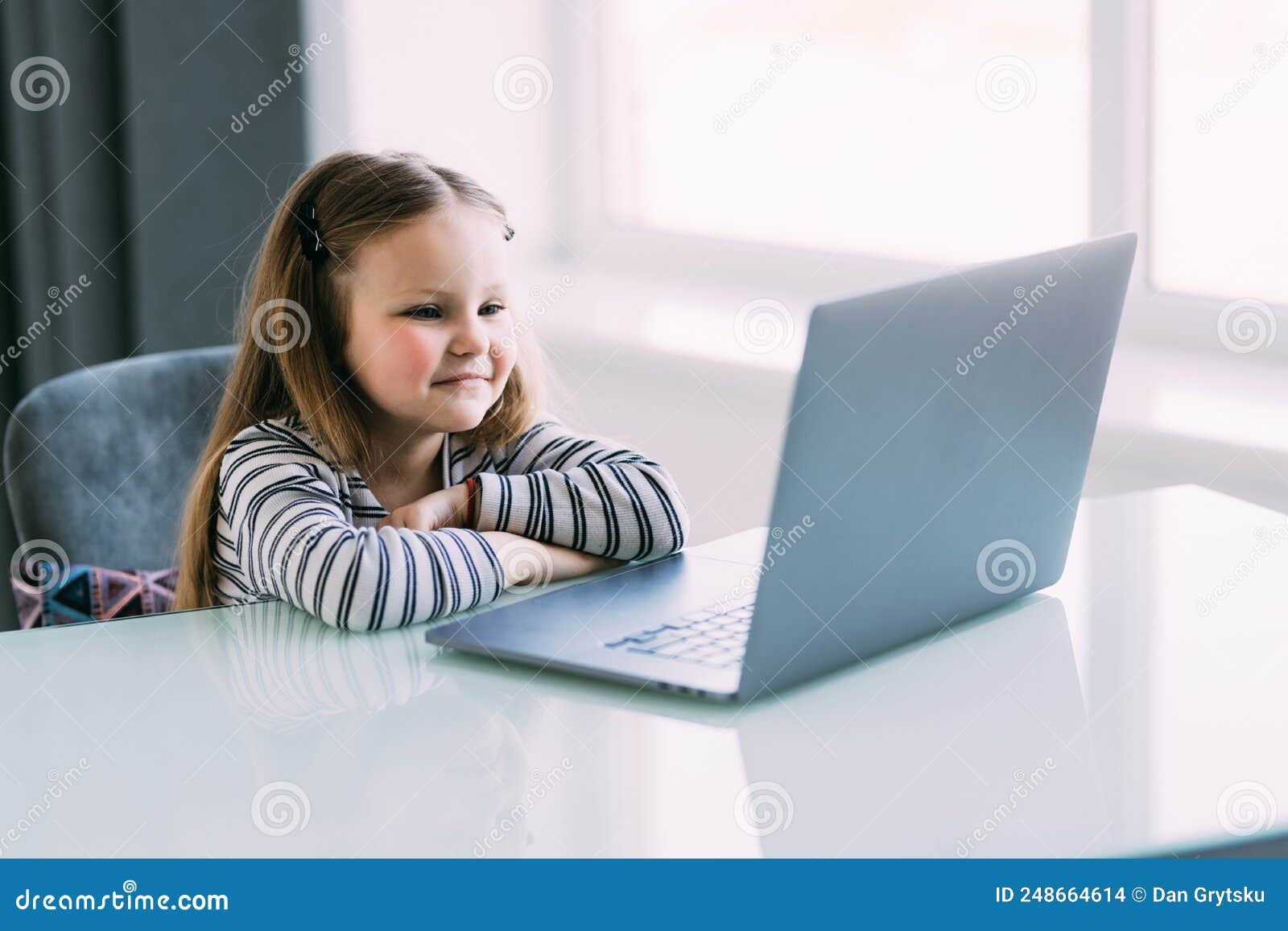 Cute Little Girl Smiling and Looking at Laptop. Little Girl Using ...