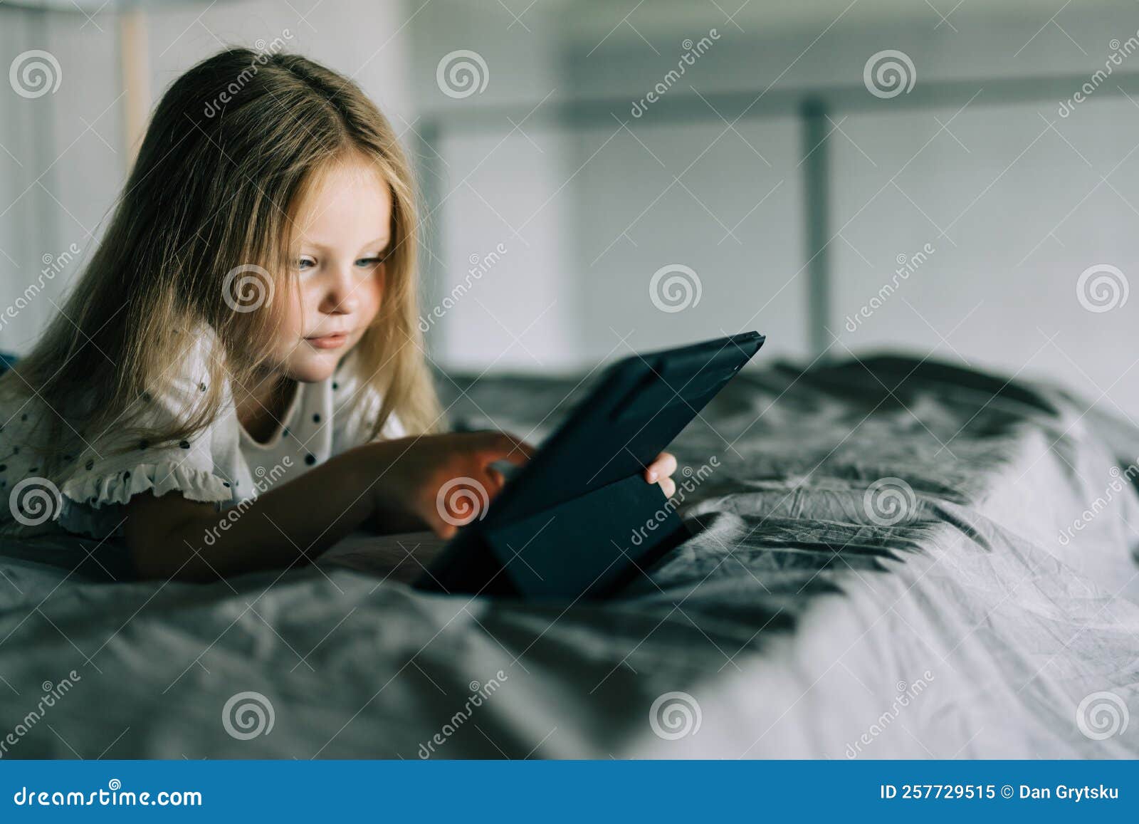 Cute Little Girl Use Digital Tablet while Lying in Bed Stock Image ...