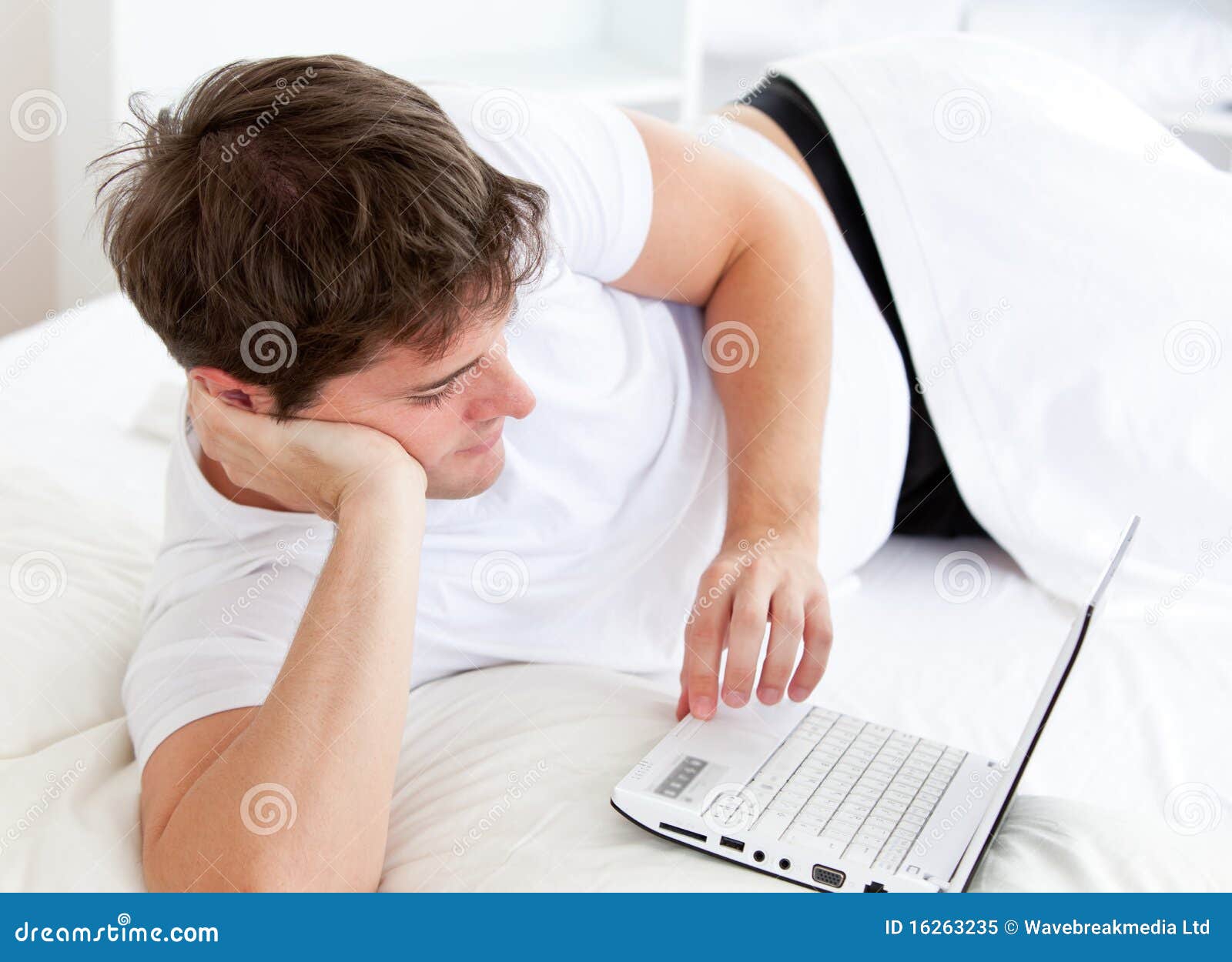 Cute Man Using a Laptop Lying on His Bed Stock Image - Image of ...