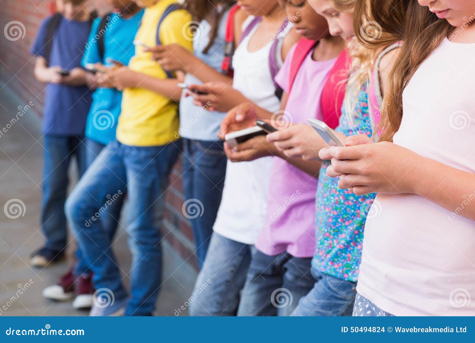 Cute Pupils Using Mobile Phone Stock Photo - Image of medium, hallway ...
