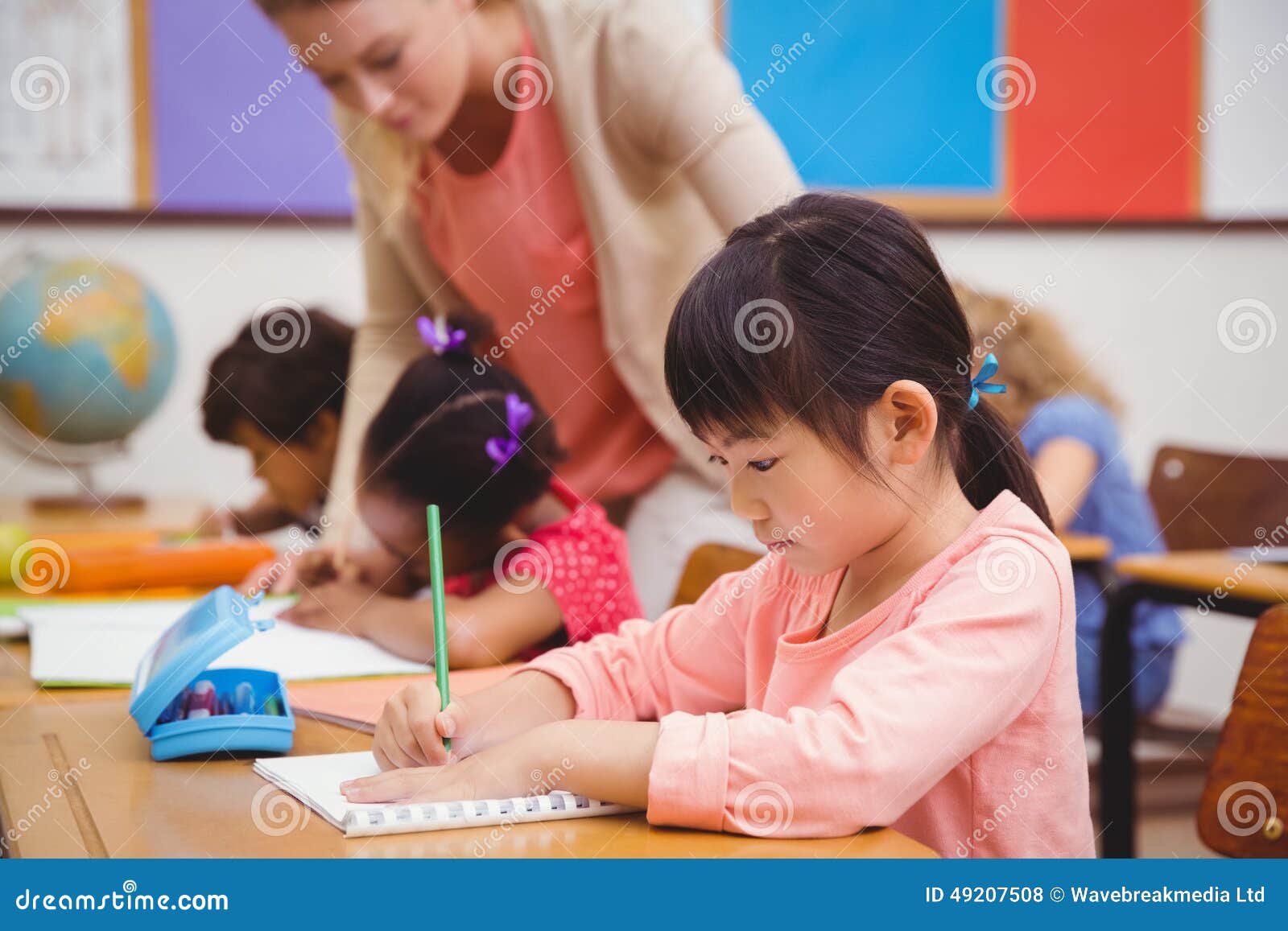 Cute Pupils Writing at Desk in Classroom Stock Photo - Image of learn ...
