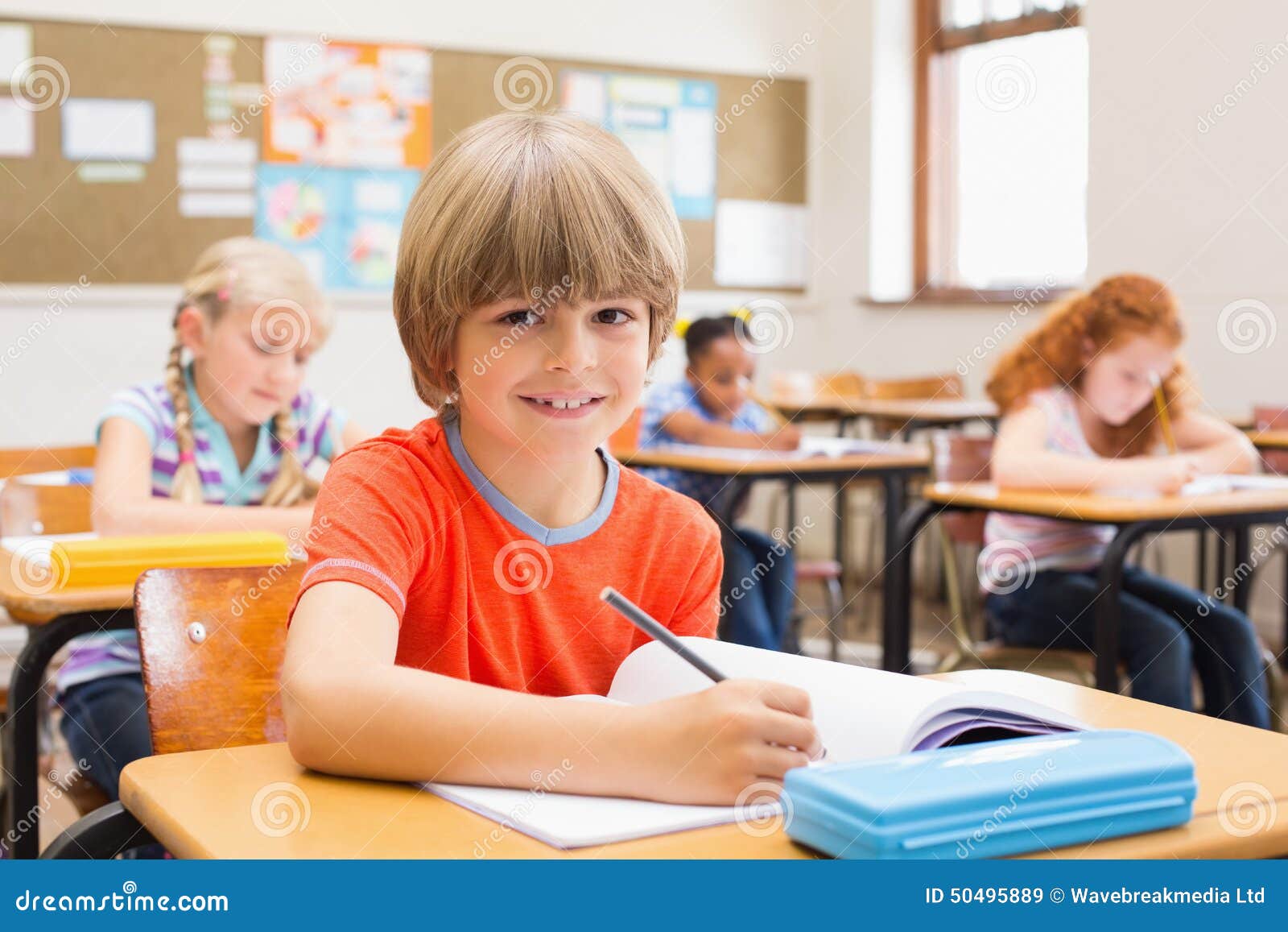 Cute Pupils Writing at Desk in Classroom Stock Image - Image of girl ...