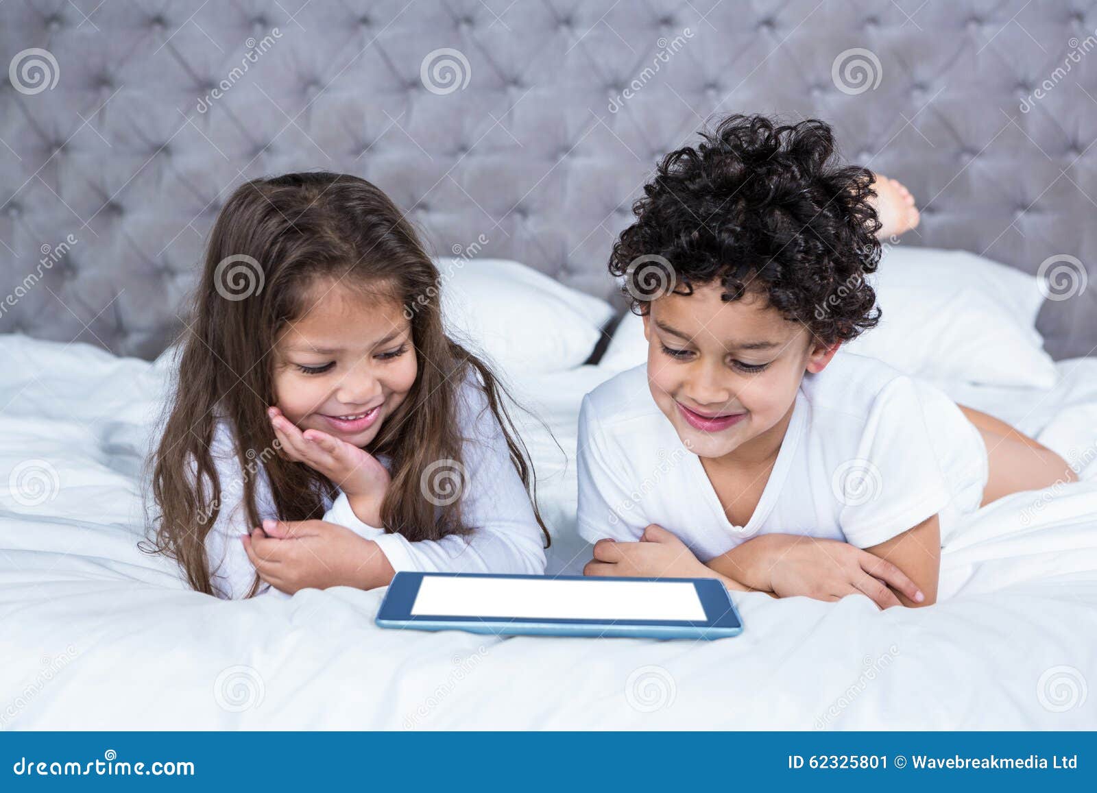 Cute Siblings Using Tablet on the Bed Stock Image - Image of female ...