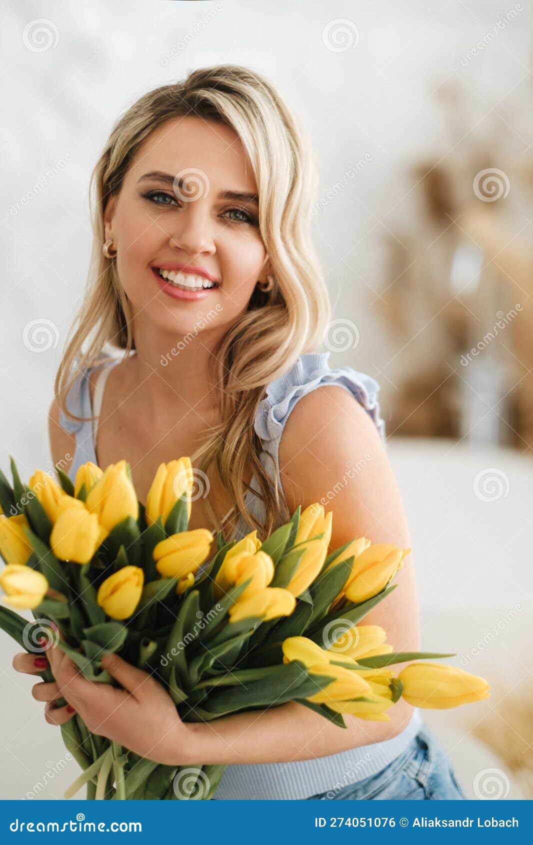 Cute Smiling Girl With A Bouquet Of Yellow Tulips In The Interior Stock