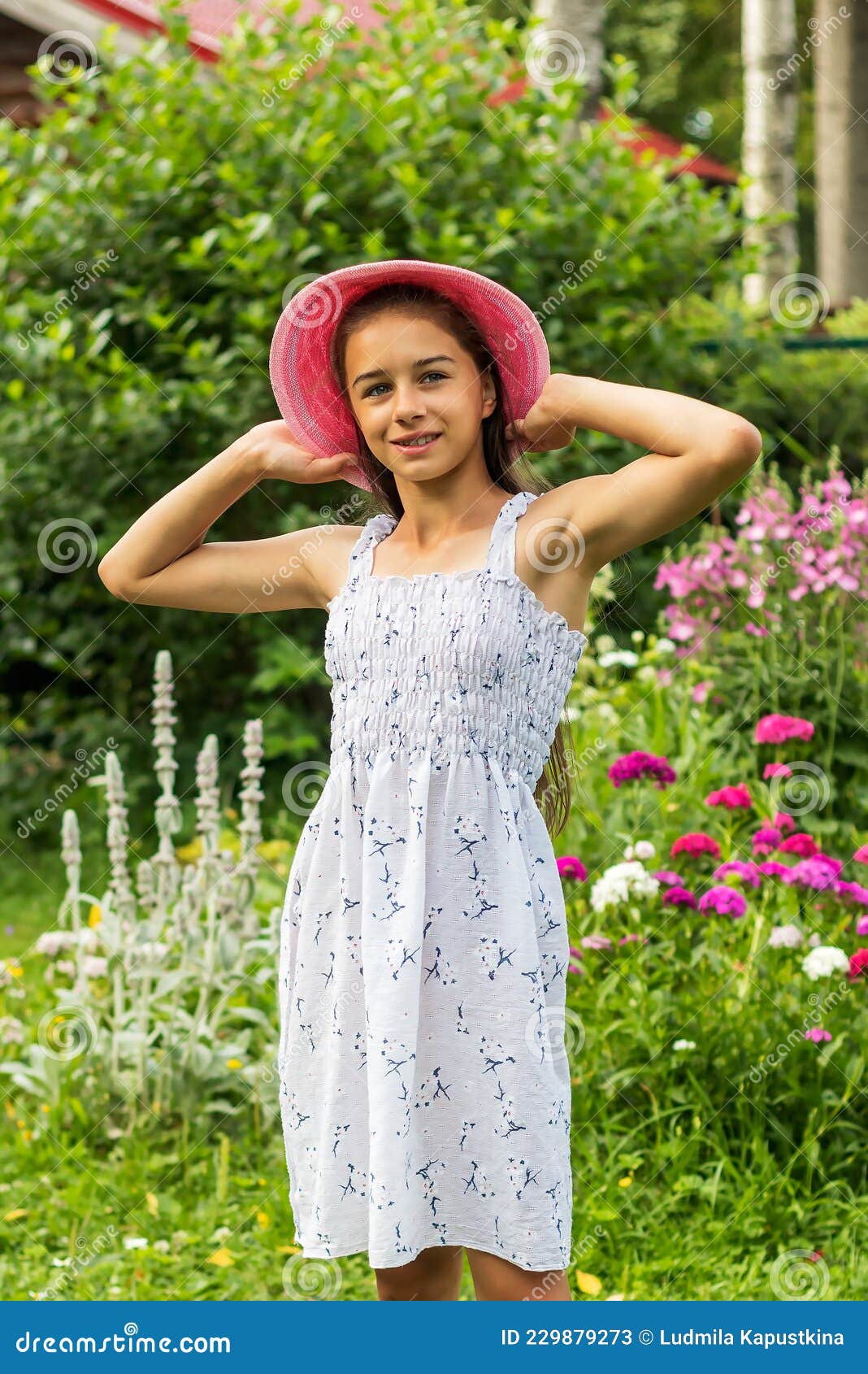 A Cute Smiling Teenage Girl In A Summer Light Sundress Stands In The