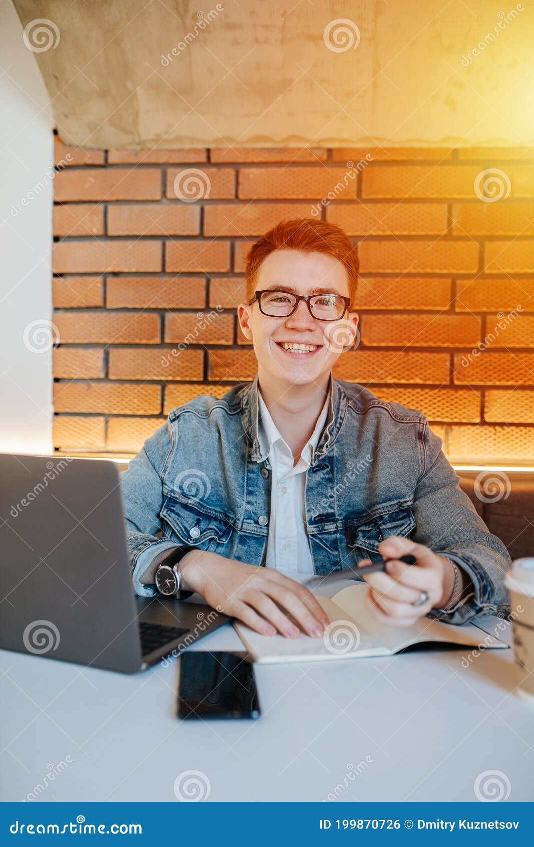 Cute Smiling Young Man in a Cafe Sitting Behind a Table with Pen and ...