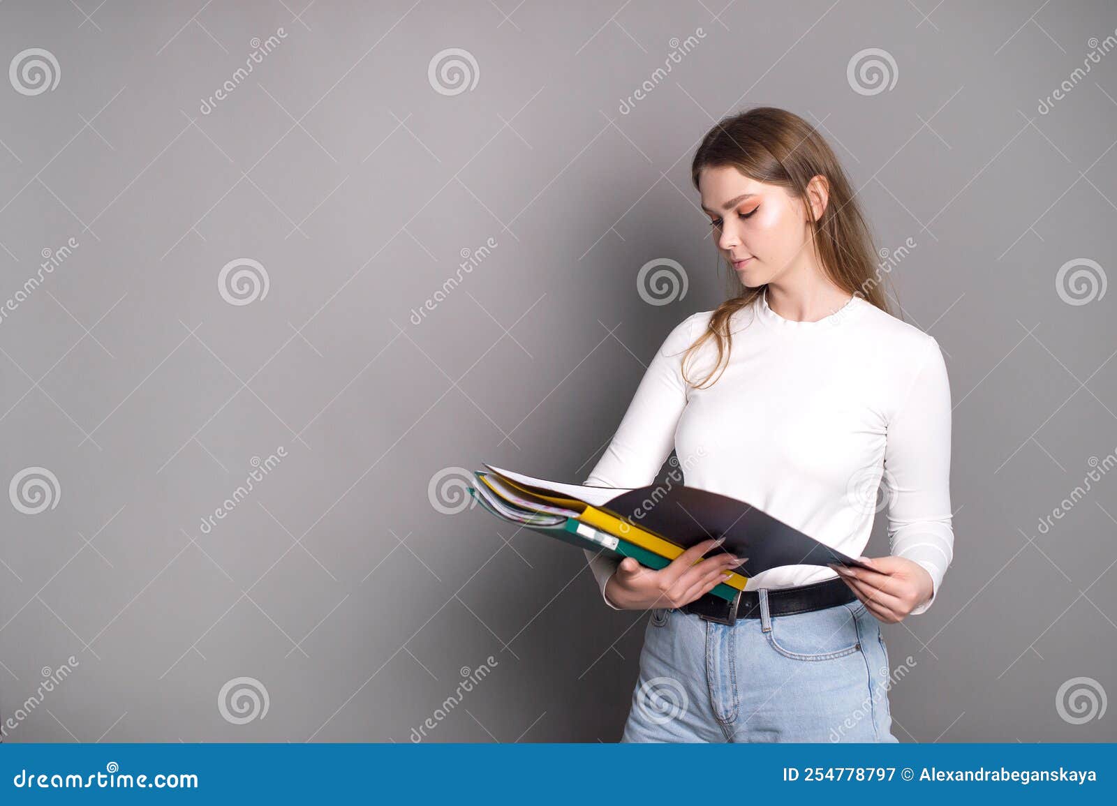 A Cute Student Girl Looks into an Open Folder for Documents and Stands ...