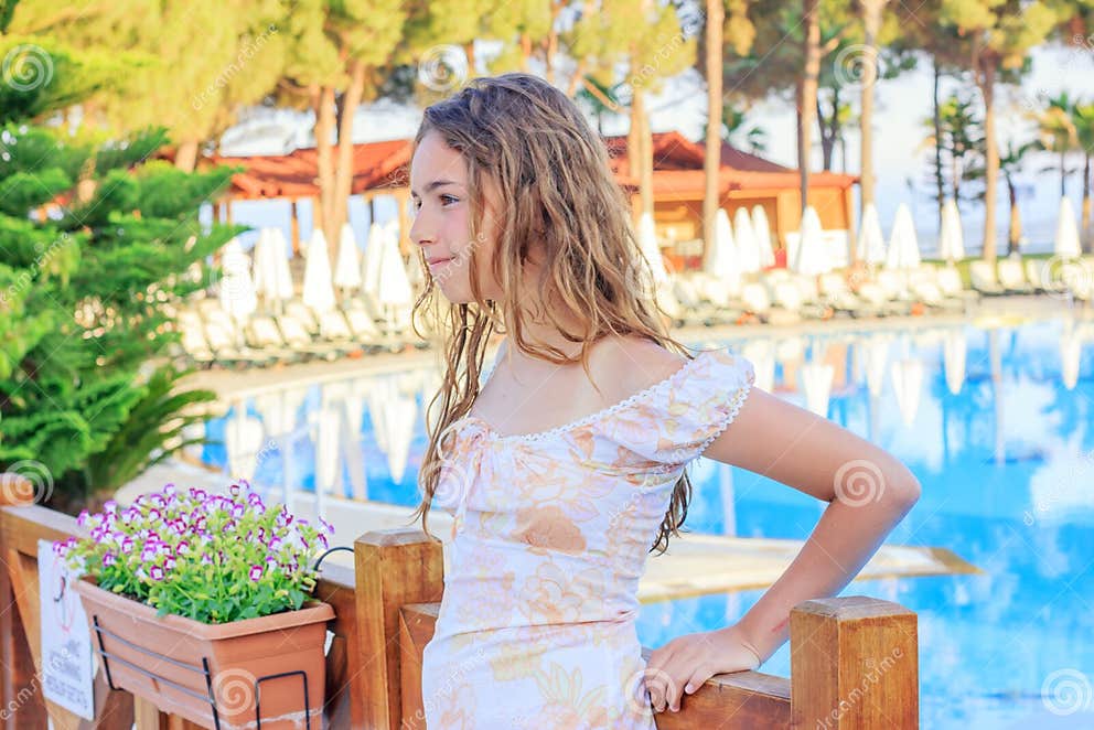 Cute Teen Girl In A Romantic Dress And With Long Hair Is Standing On
