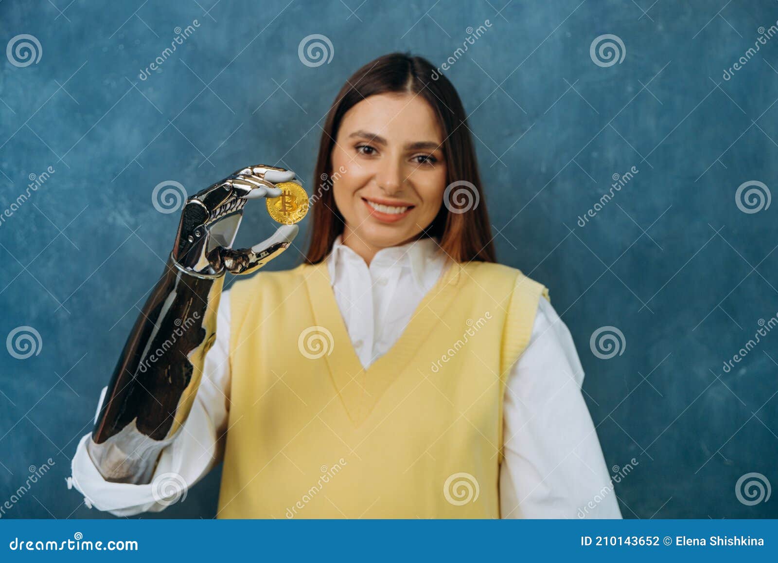 Cute Woman With A Bionic Prosthetic Arm Holds A Gold Bitcoin Coin And Smiles On A Blue