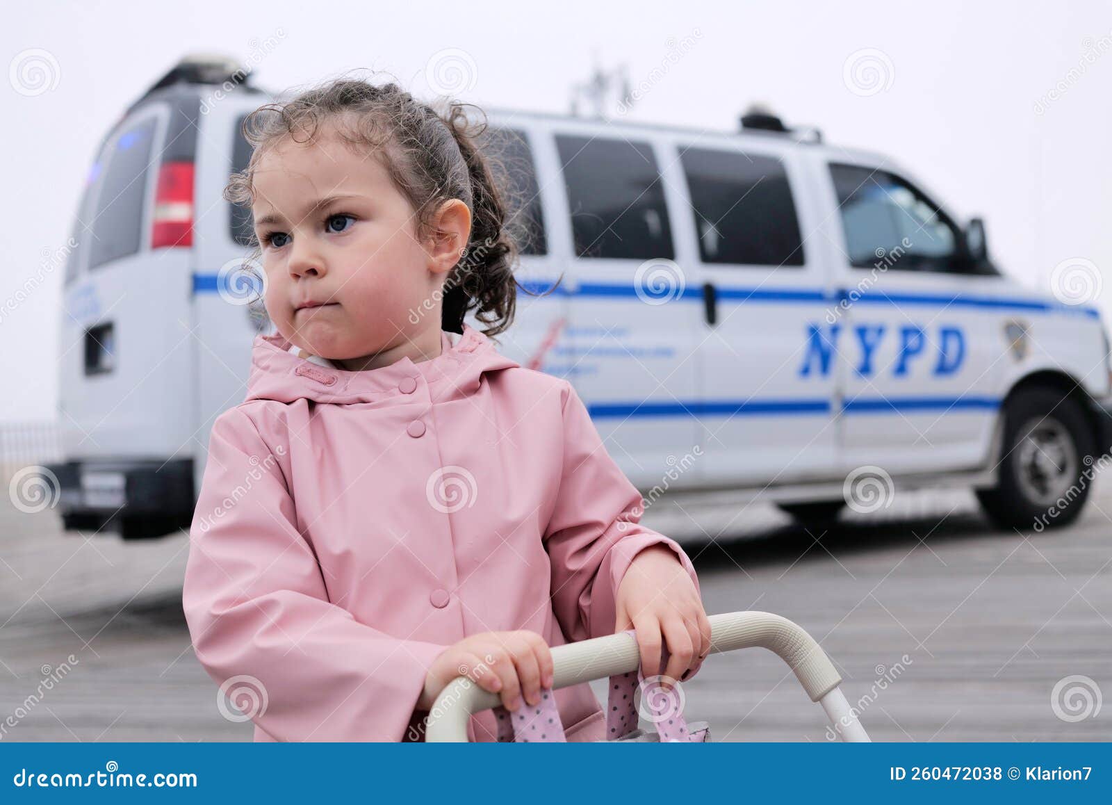 Cute Young Girl Playing With Her Toy Stroller On The Boarwalk As A