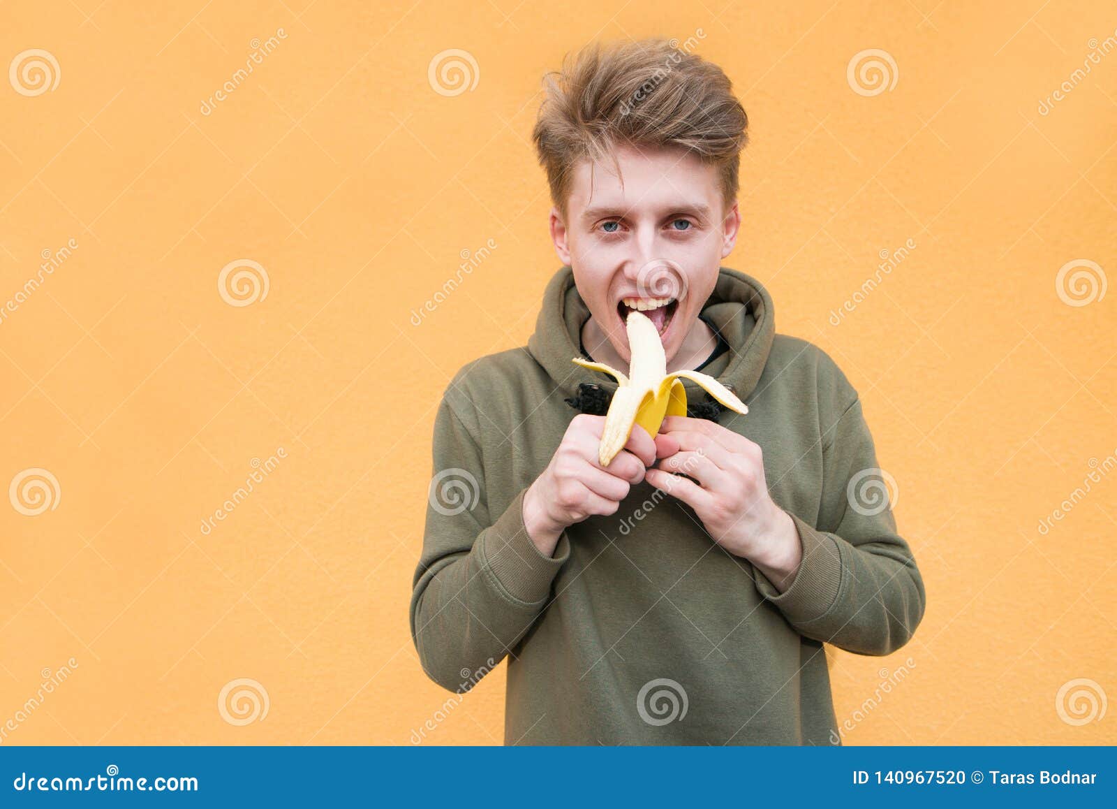 Cute Young Man Bites a Banana on the Background of an Orange Wall and ...