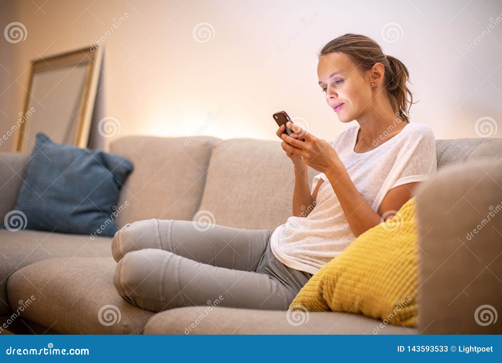 Cute Young Woman on a Comfortable Sofa Using Her Cell Phone Stock Image ...
