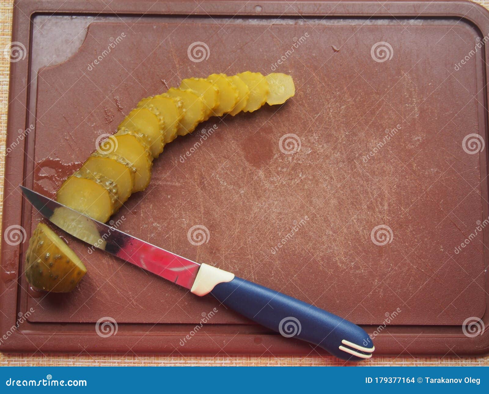 On the Cutting Board are a Pickle and a Knife. the Pickle is Cut into ...