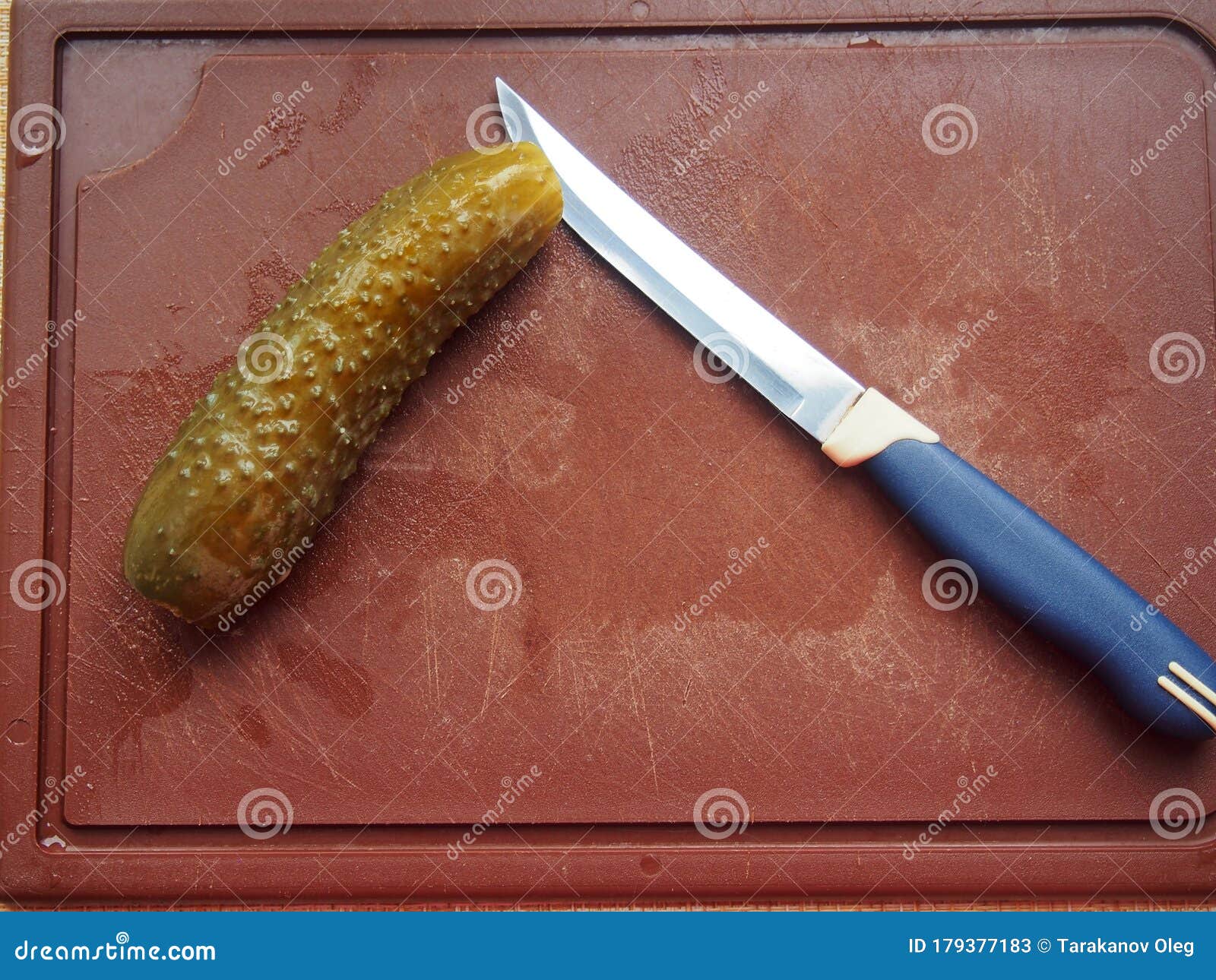 On the Cutting Board are a Pickle and a Knife. the Pickle is Cut into ...