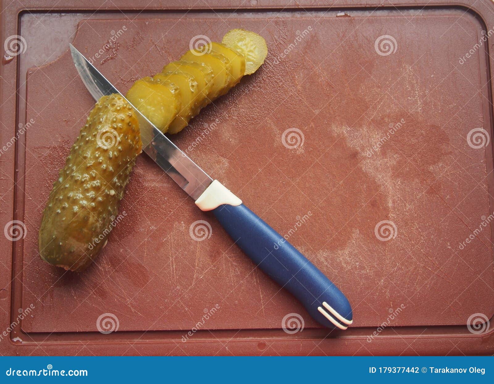On the Cutting Board are a Pickle and a Knife. the Pickle is Cut into ...