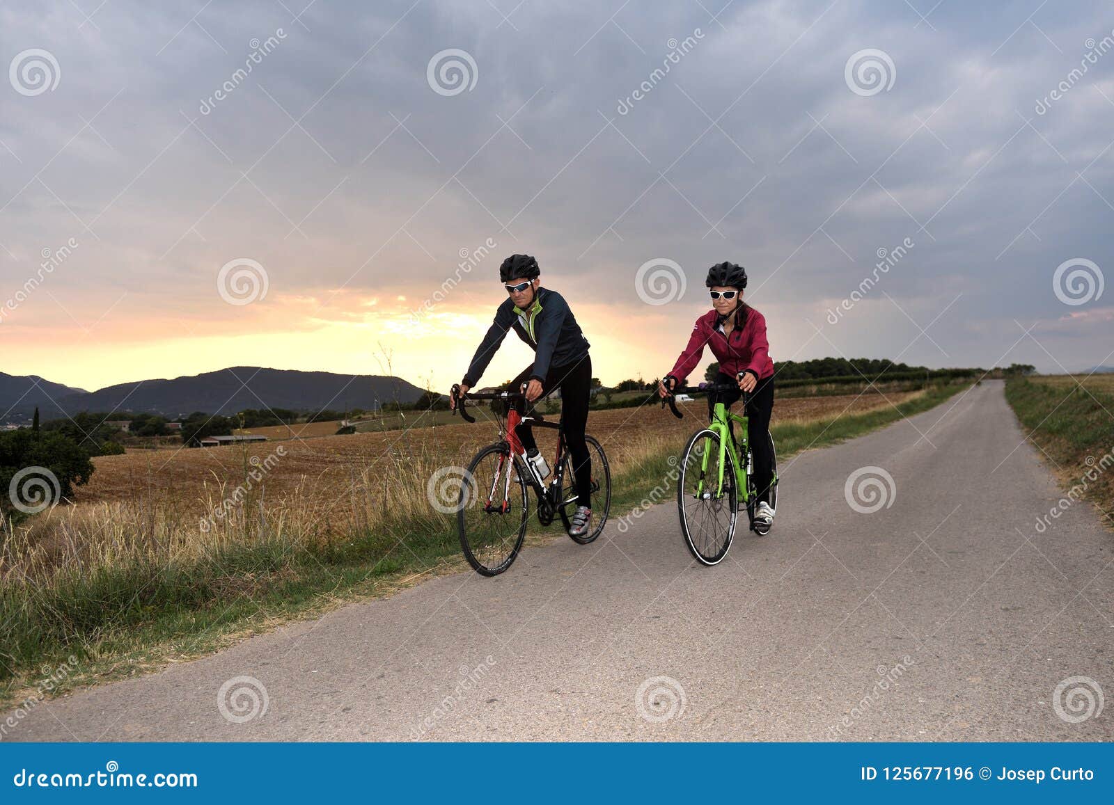 Cycling couple on a road stock photo. Image of afternoon - 125677196