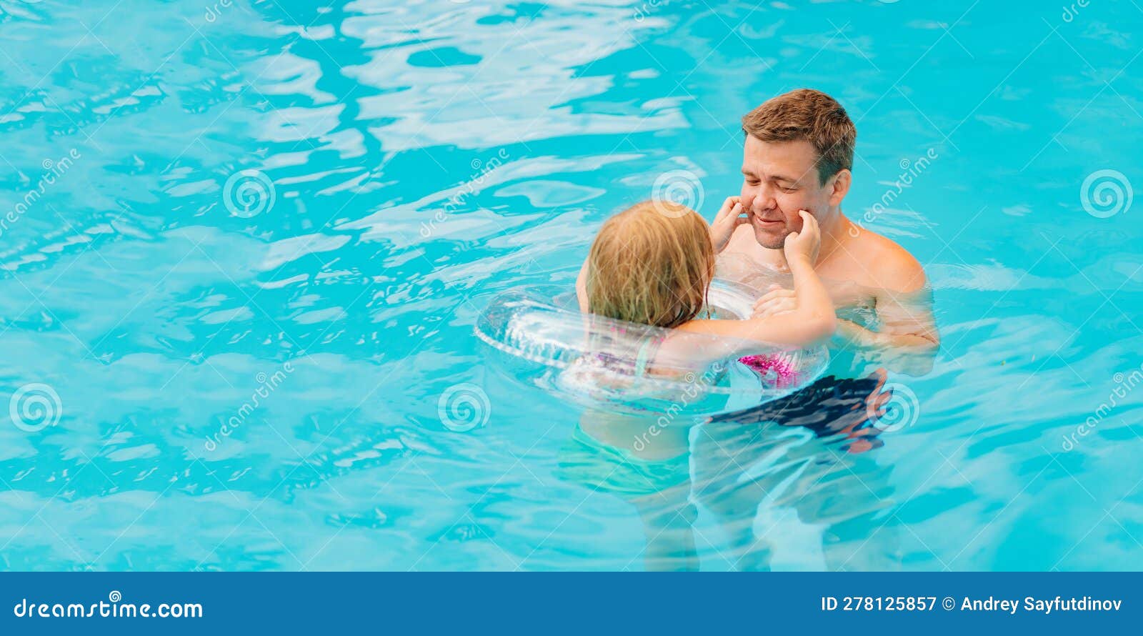 Dad And Daughter Have Fun And Swim With Inflatable Circle In The Pool