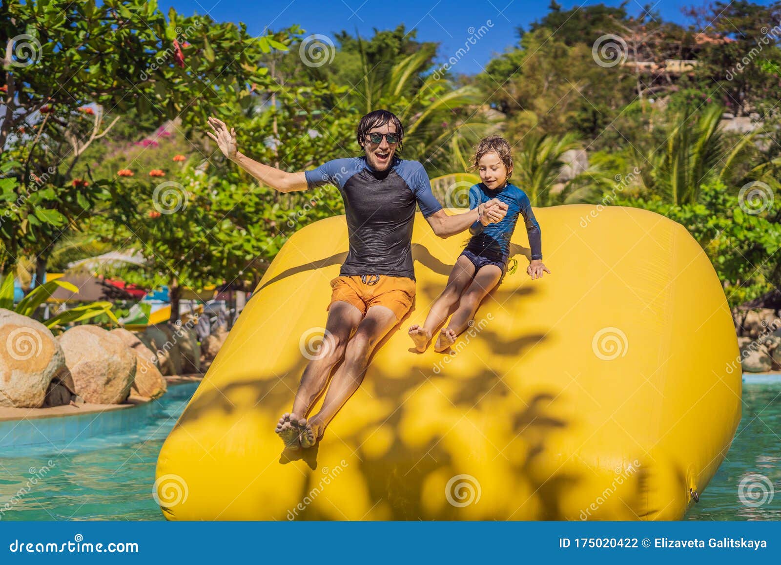 Dad and Son Go through an Inflatable Obstacle Course in the Pool Stock ...