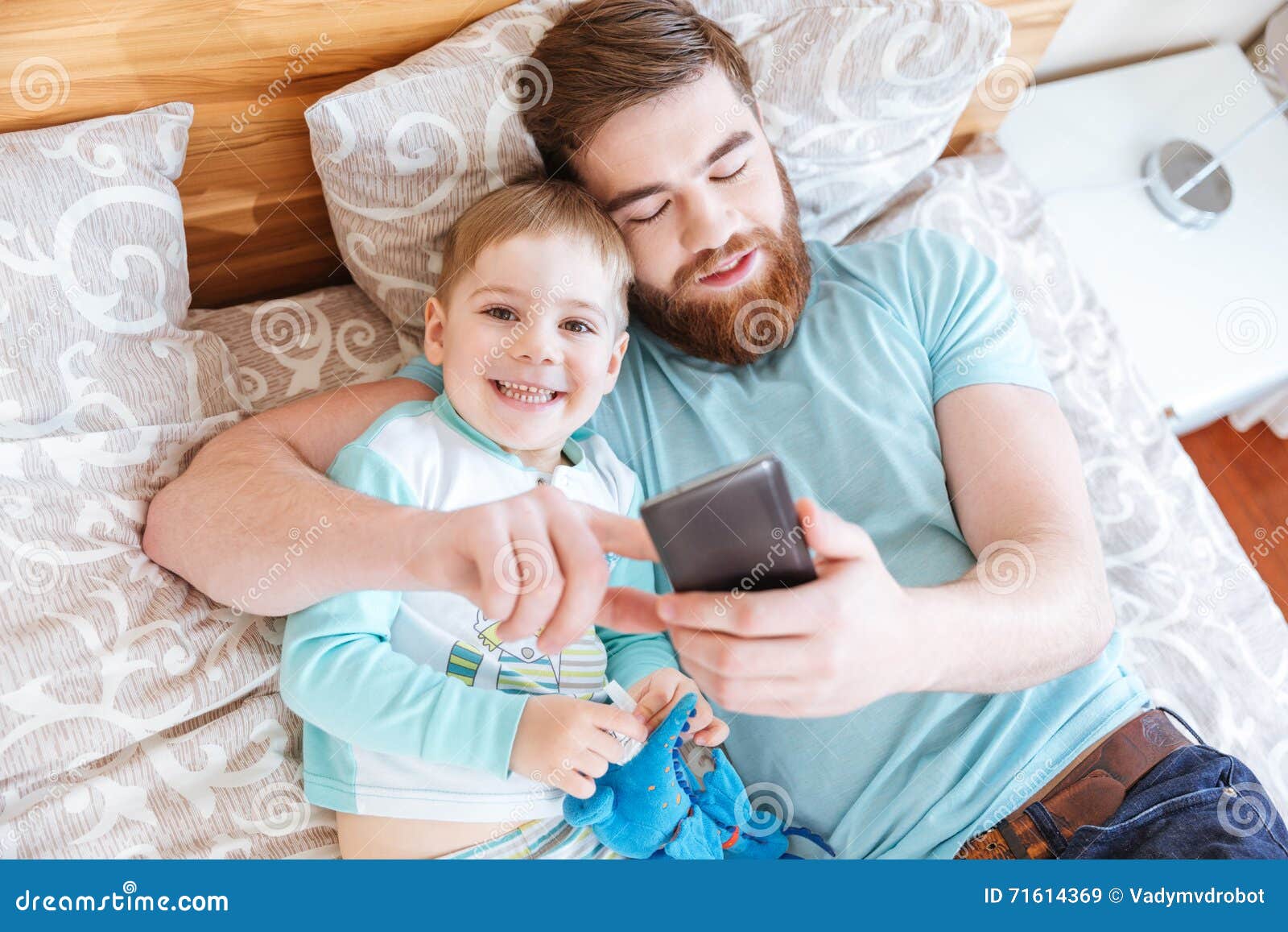 Dad and Son Using Cell Phone on Bed Together Stock Image - Image of ...