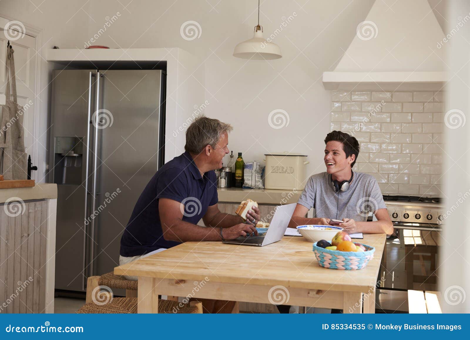 Dad and Son Using Technology Eat and Talk at Kitchen Table Stock Image ...