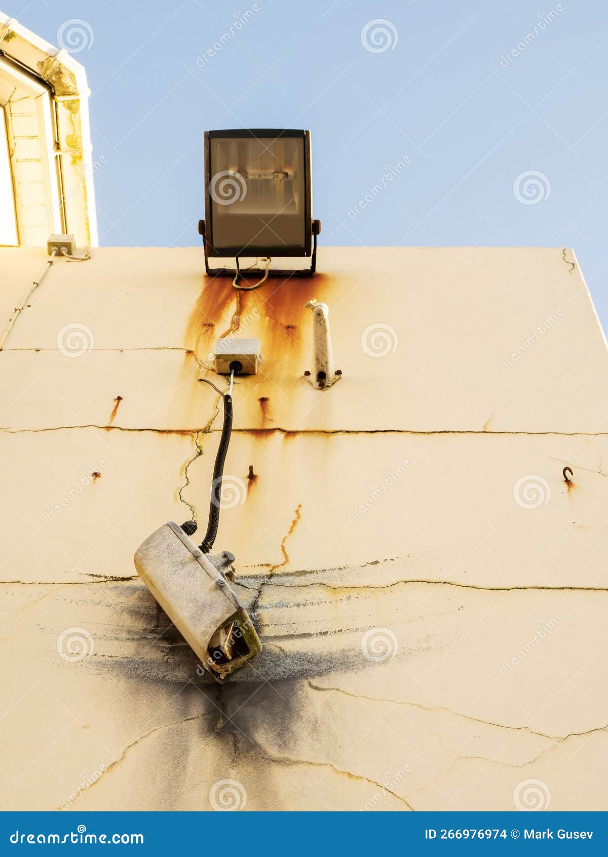 Damaged CCTV Camera Hanging on a Cable on Yellow Wall, Old Flood Light ...