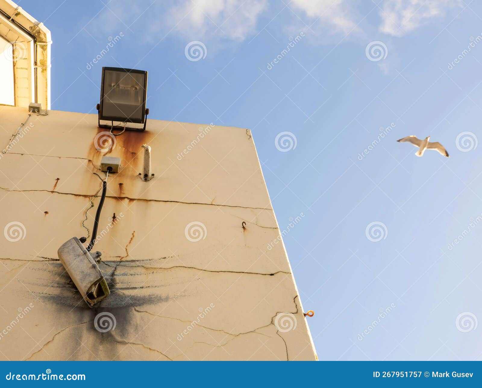 Damaged CCTV Camera Hanging on a Cable on Yellow Wall, Old Flood Light ...