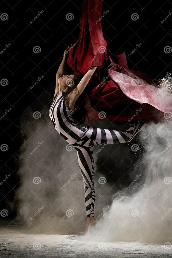 Dancer Performs Dynamic Movement with Red Fabric in a Dramatic Setting ...