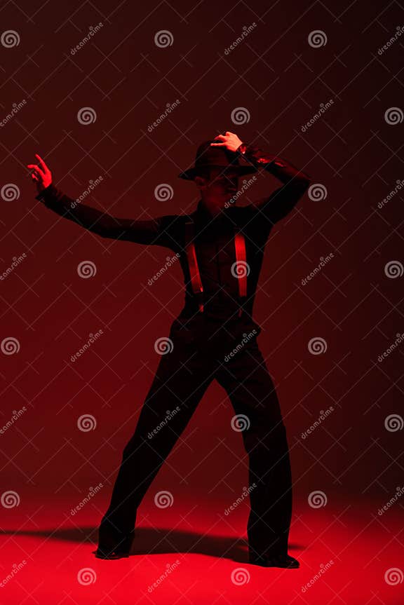 Dancer Touching Hat while Performing Tango on Dark Background with Red ...