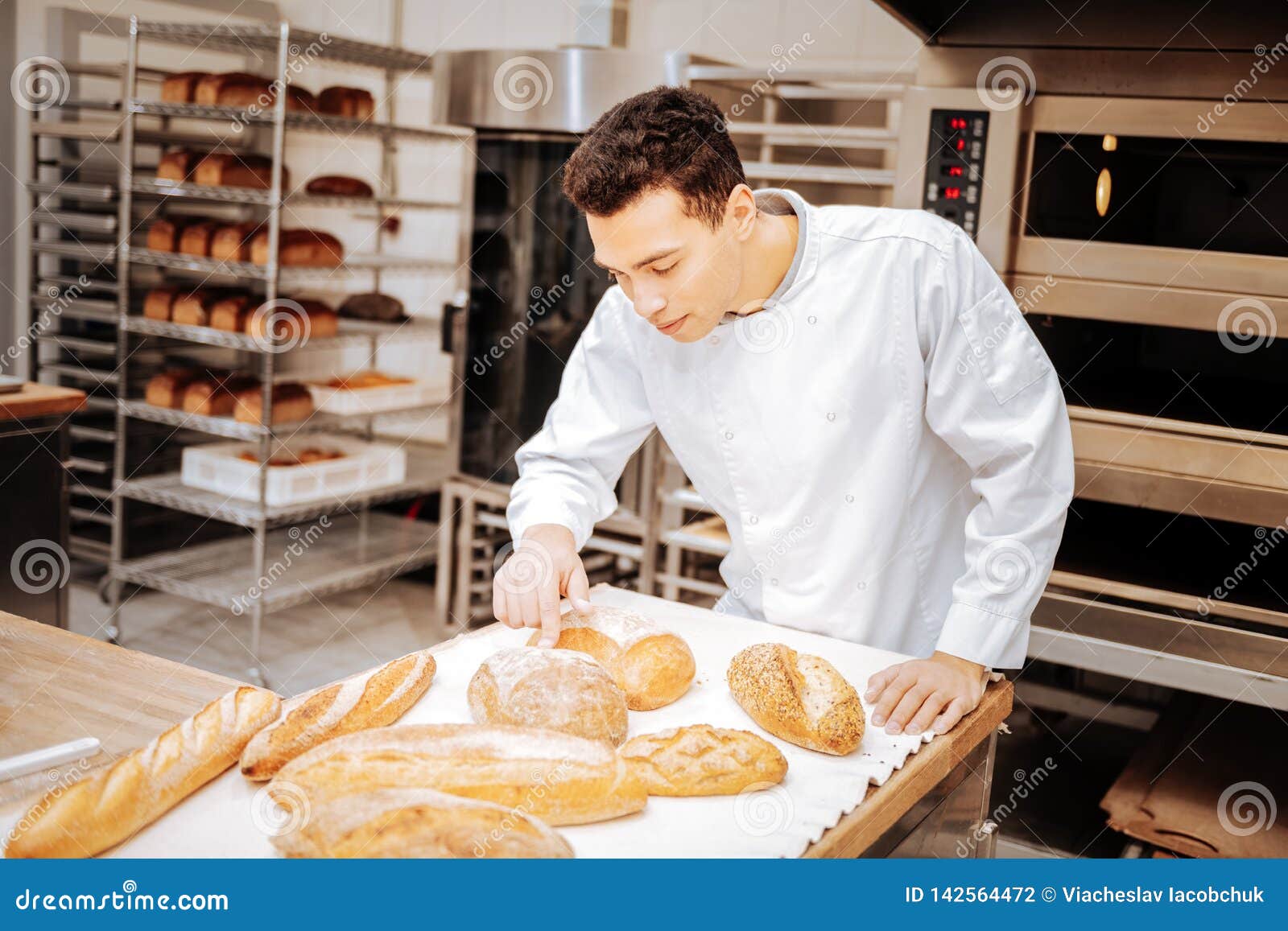 Dark-haired Baker Touching the Loaf of Bread after Baking the Tray ...