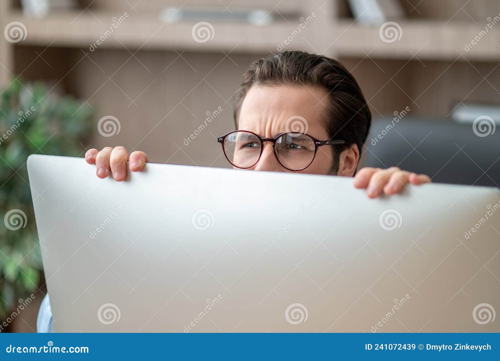 A Dark-haired Man Hiding Behind the Computer and Looking Stressed Stock ...