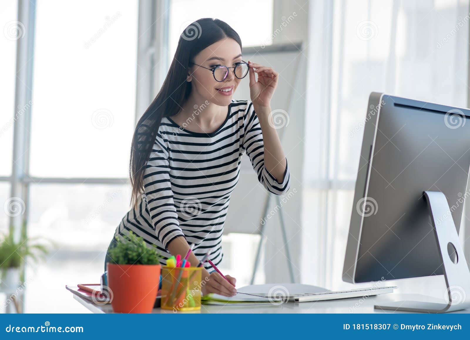 Dark-haired Woman in a Striped Shirt Looking at the Computers Screen ...
