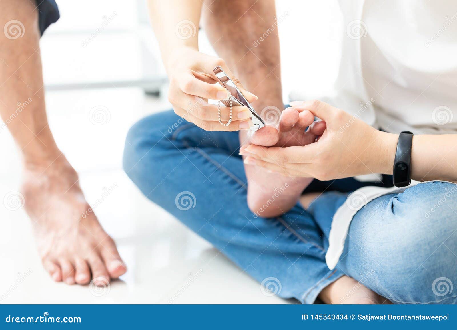 The Daughter’s Hand Holds A Nail Clipper Cutting The Toenails For Her