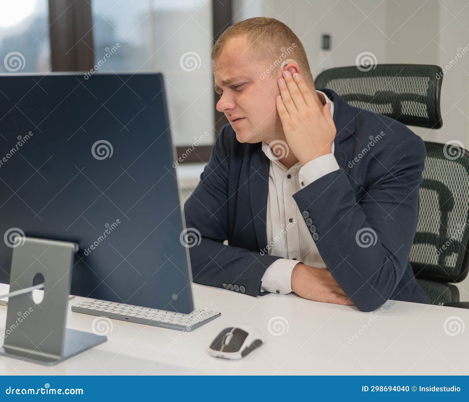 A Deaf Man Works at a Computer in the Office. Broken Hearing Aid ...