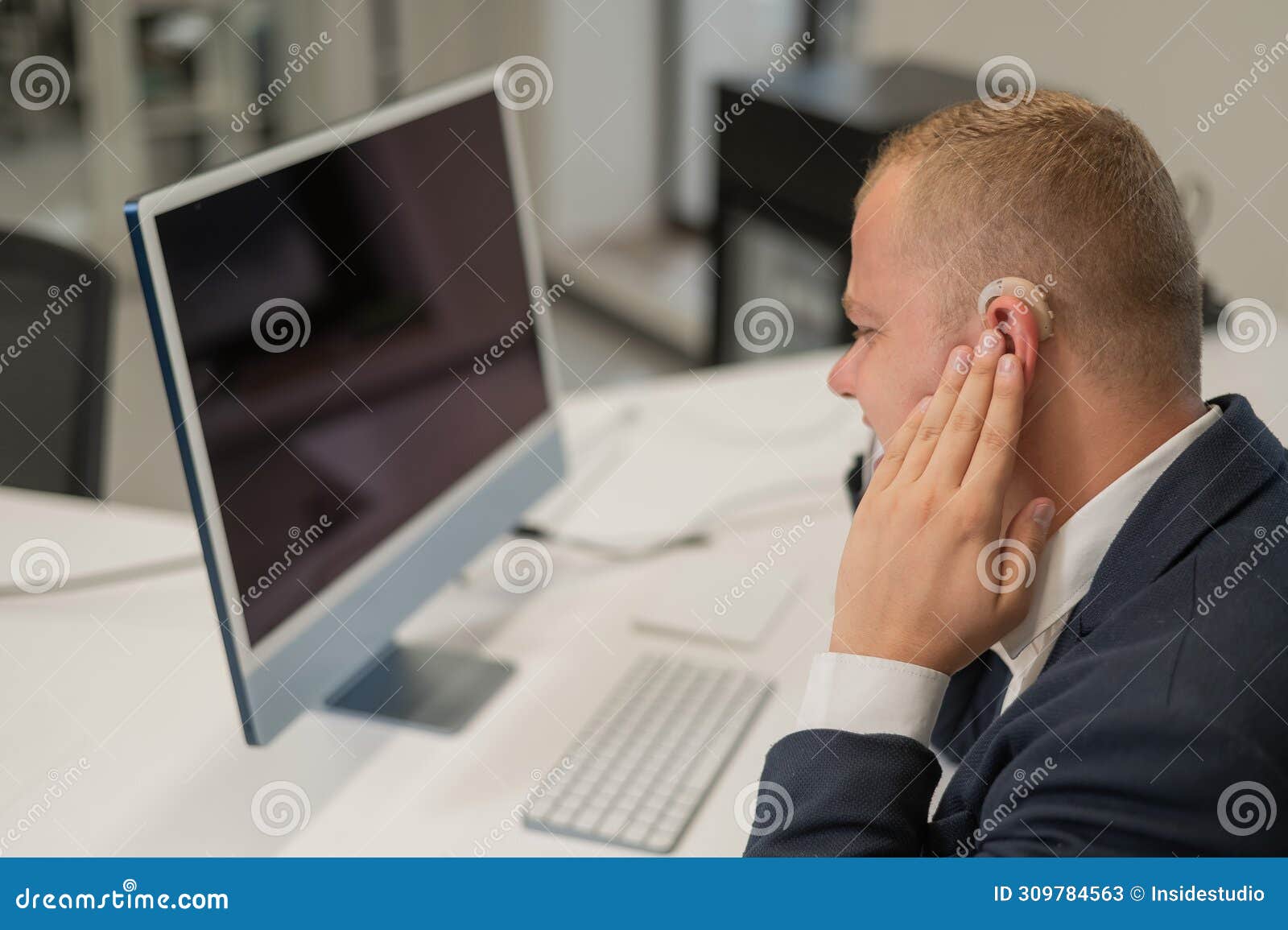 A Deaf Man Works at a Computer in the Office. Broken Hearing Aid ...
