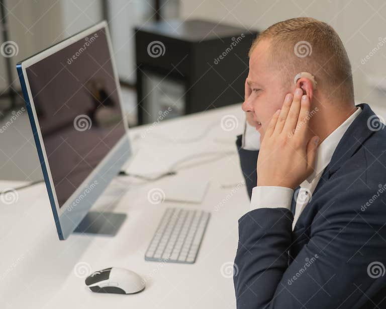A Deaf Man Works at a Computer in the Office. Broken Hearing Aid ...