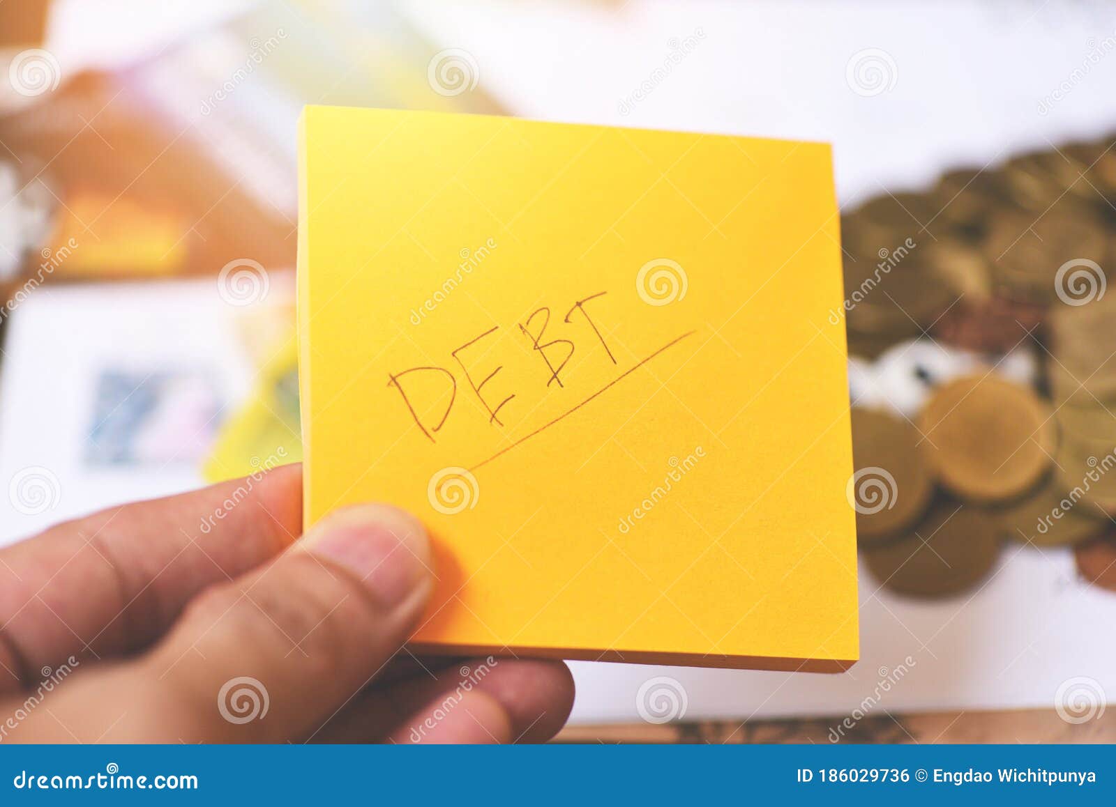 Debt Concept with Write Debt on Paper in Hand and Coins on Table ...