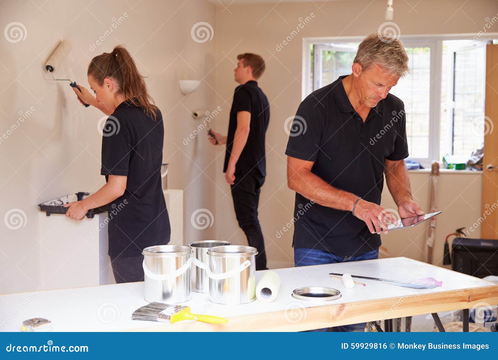 Decorating Team Painting a Room and Using Tablet Computer Stock Photo ...