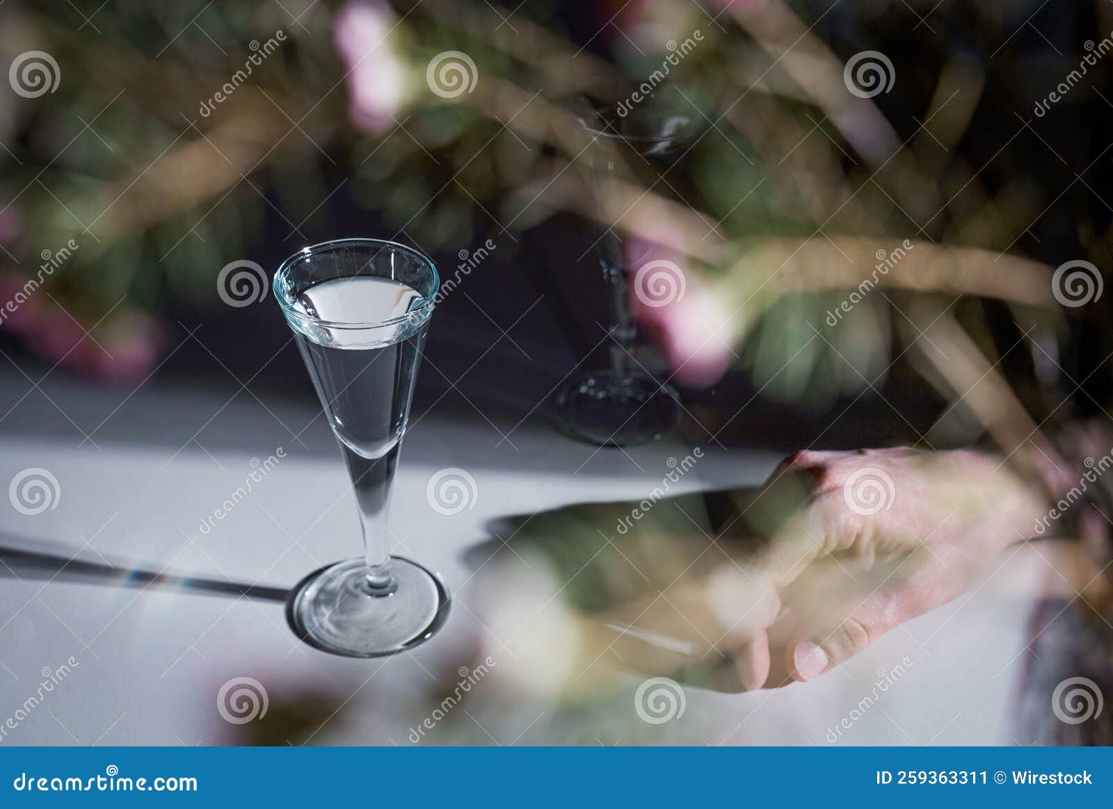 Decorative Elegant Glass with a Clear Liquid on a Table with a Hand ...