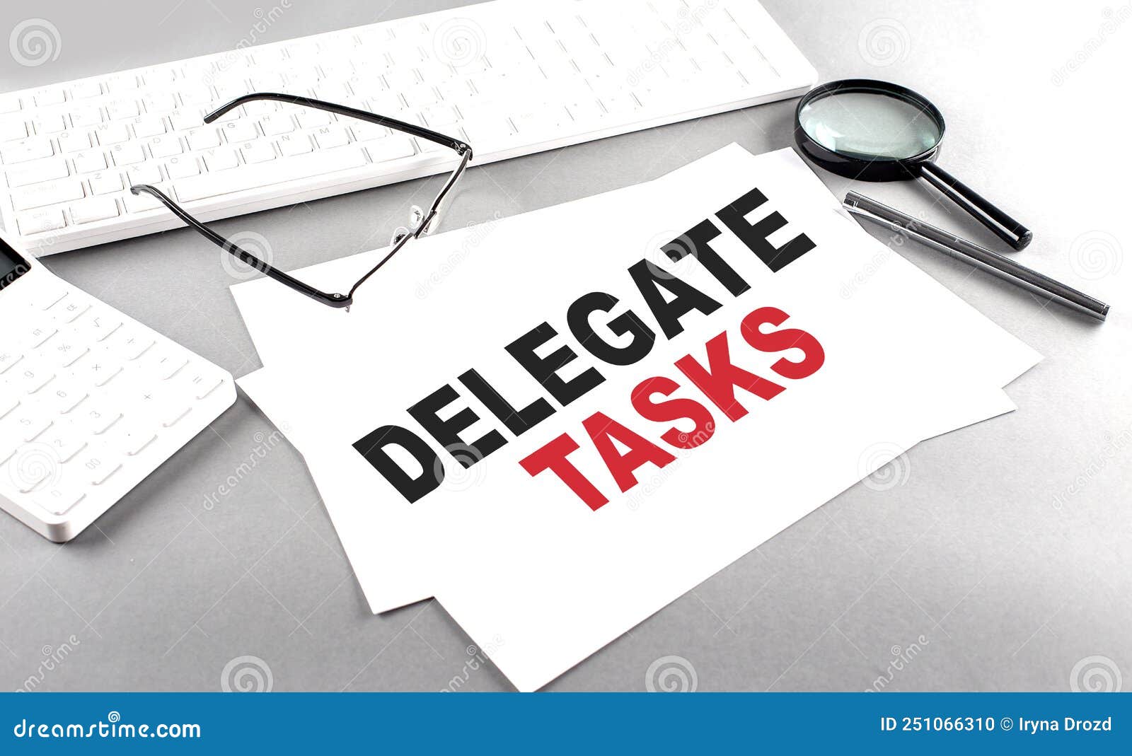 DELEGATE TASKS Text on a Paper on a Gray Background Near a Calculator ...