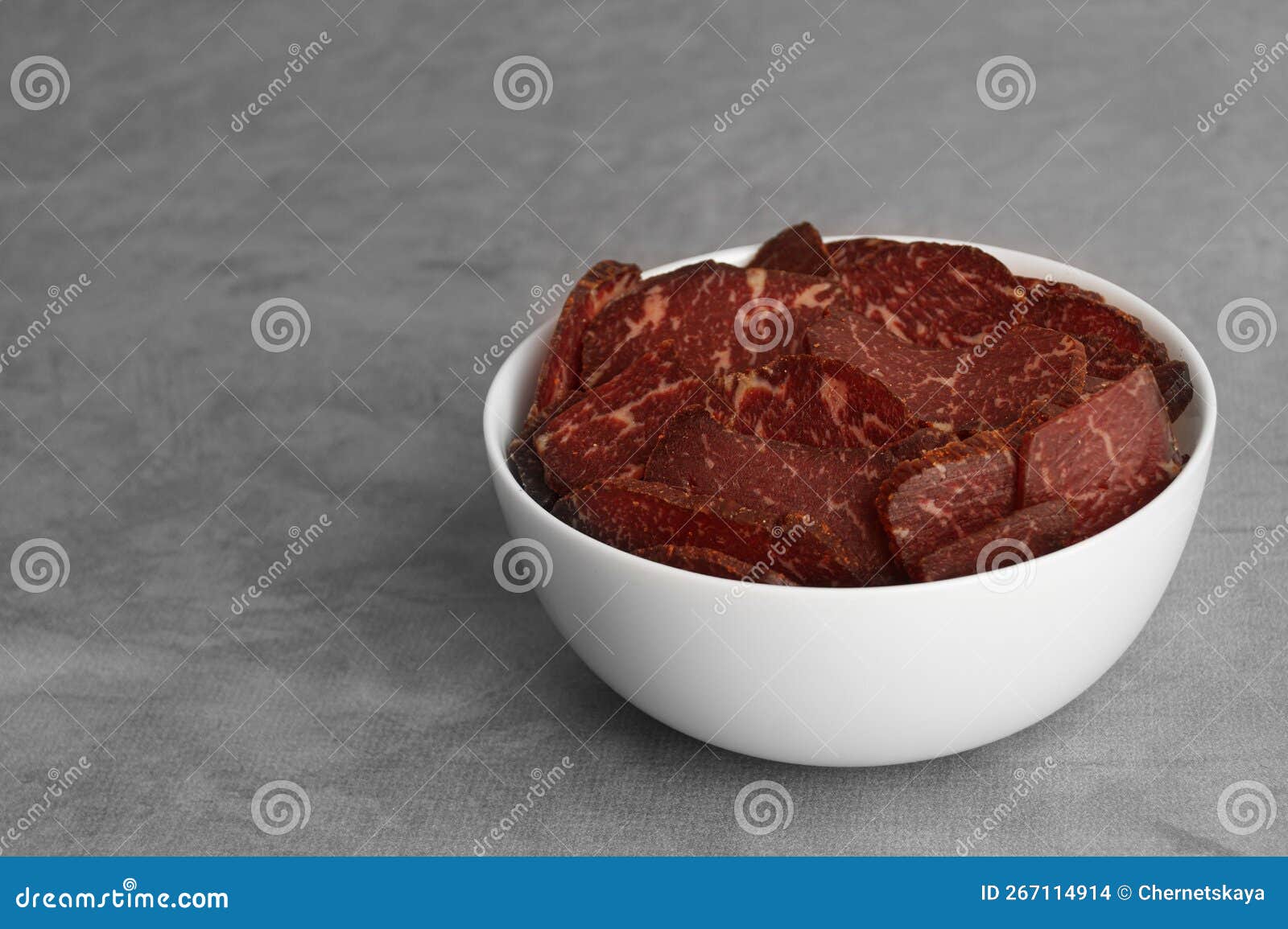 Delicious Beef Jerky in Bowl on Light Gray Table, Space for Text Stock ...