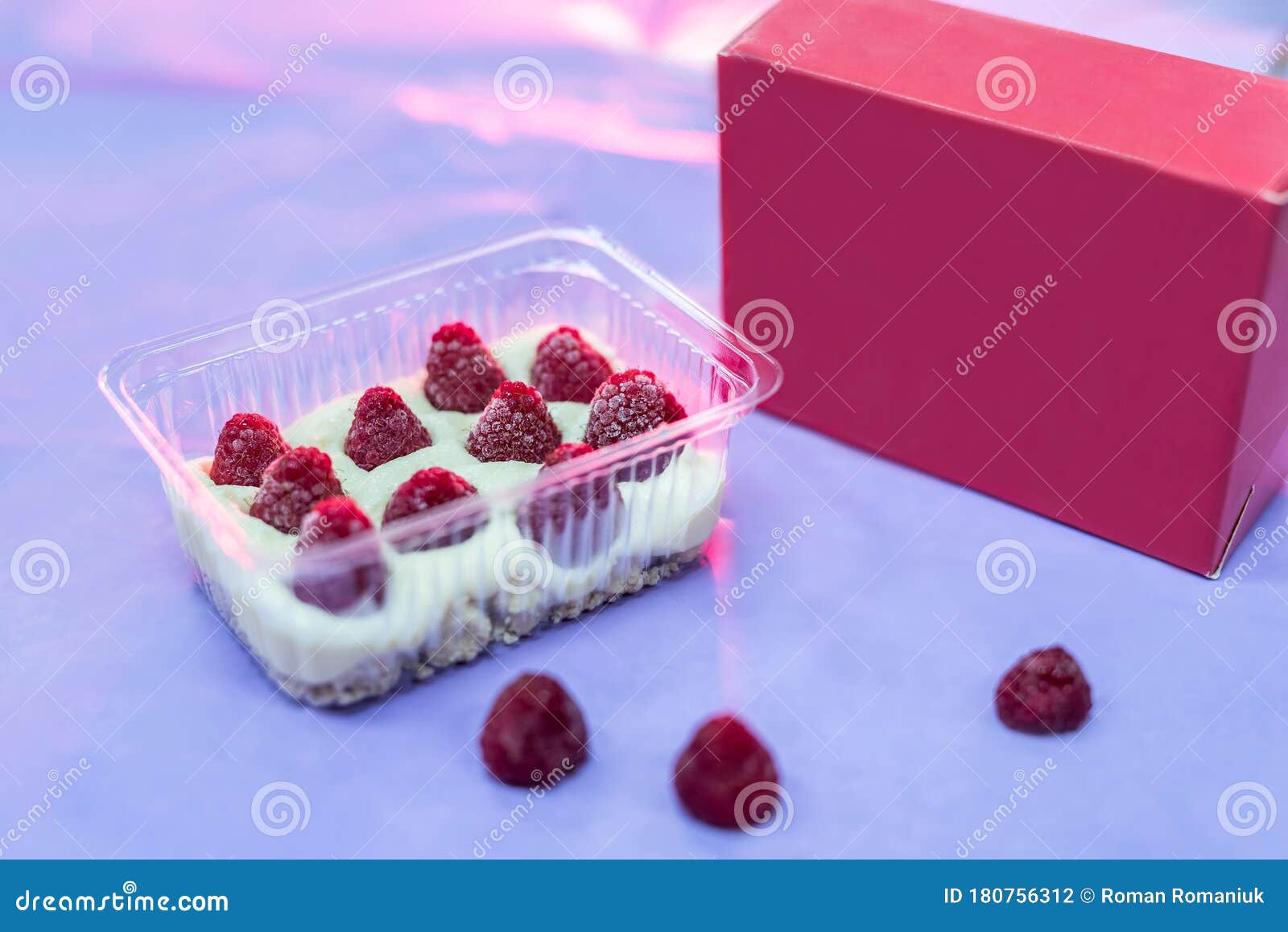 Delicious Dessert in Plastic Package with Raspberry on Table and Pink ...
