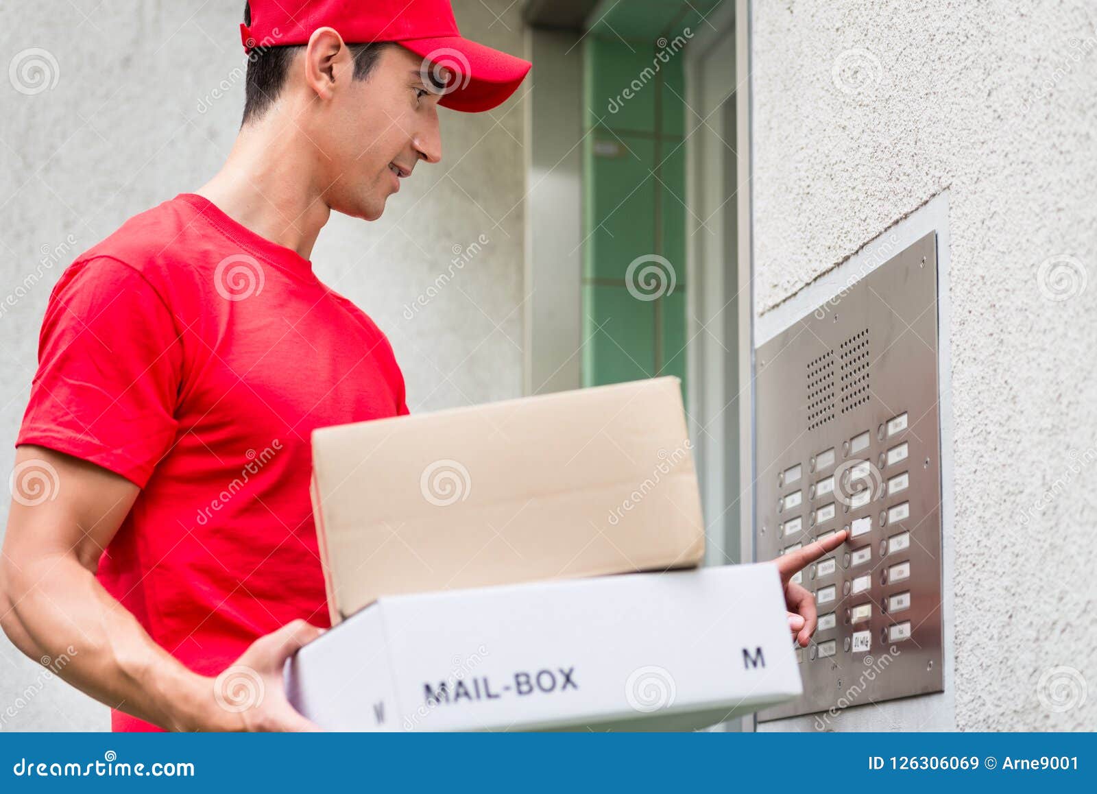 Delivery Man Carrying Mail Packages Using the Intercom Stock Image ...