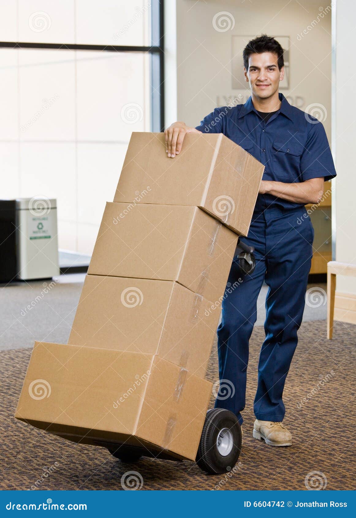 Delivery Man in Uniform Pushing Stack of Boxes Stock Photo - Image of ...