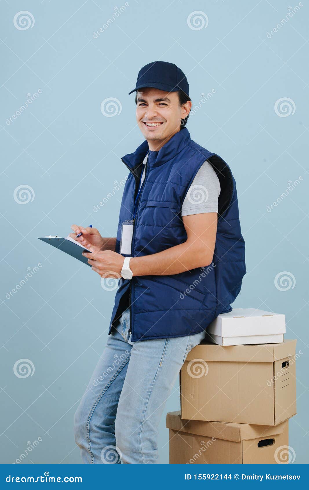 Delivery Man in Uniform is Seating on a Stack of Parcel Cardboard Boxes ...
