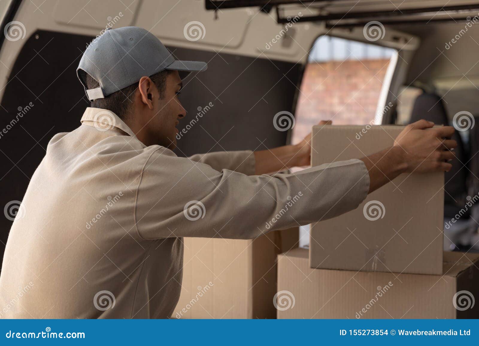 Delivery Man Unloading Cardboard Boxes from a Van Outside the Warehouse ...