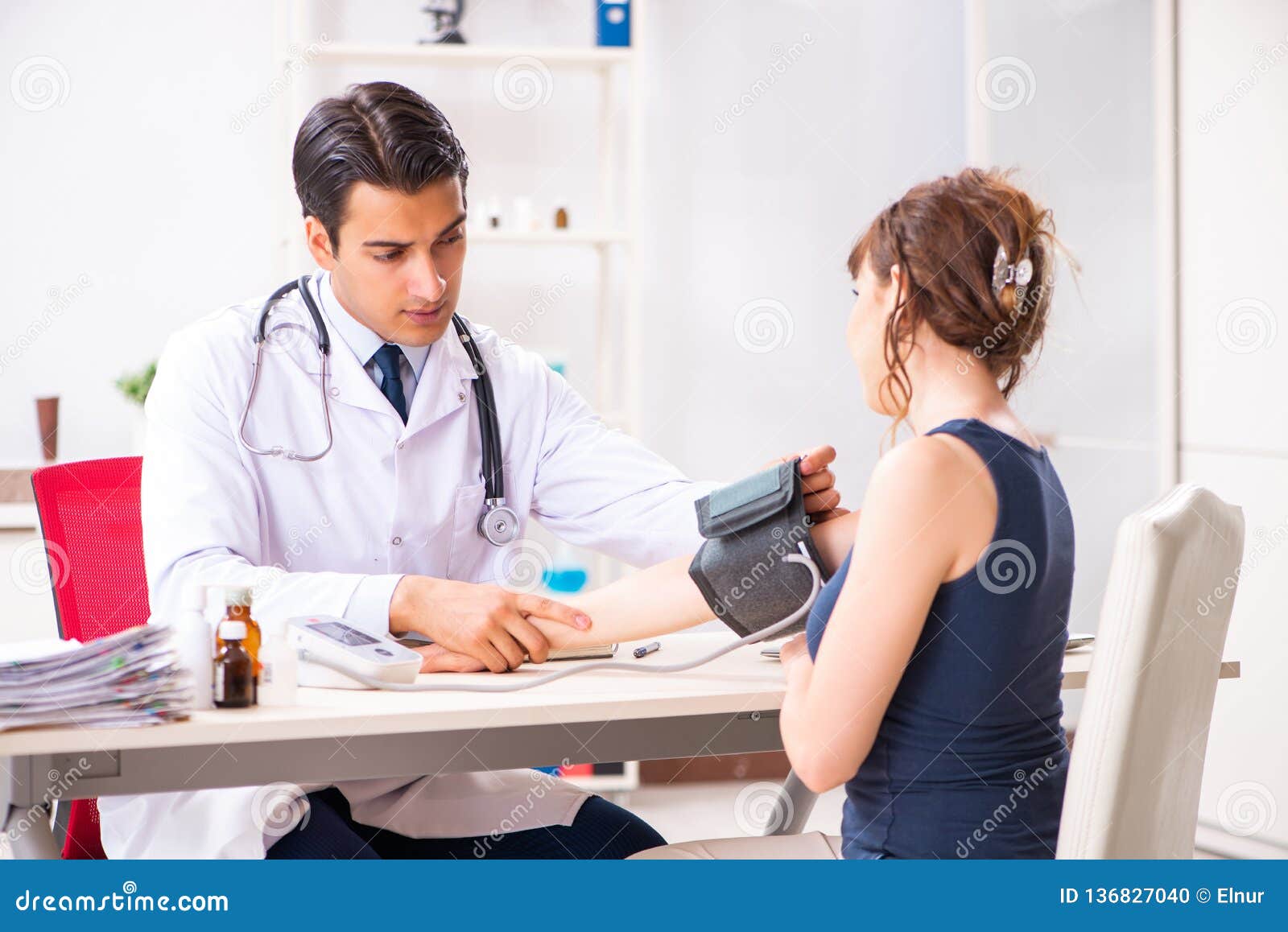Den Unga Doktorn Som Kontrollerar Kvinnas Blodtryck Arkivfoto - Bild av ...