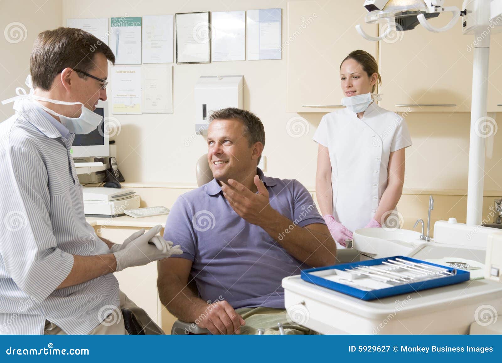 Dentist and Assistant in Exam Room with Man Stock Image - Image of mask ...