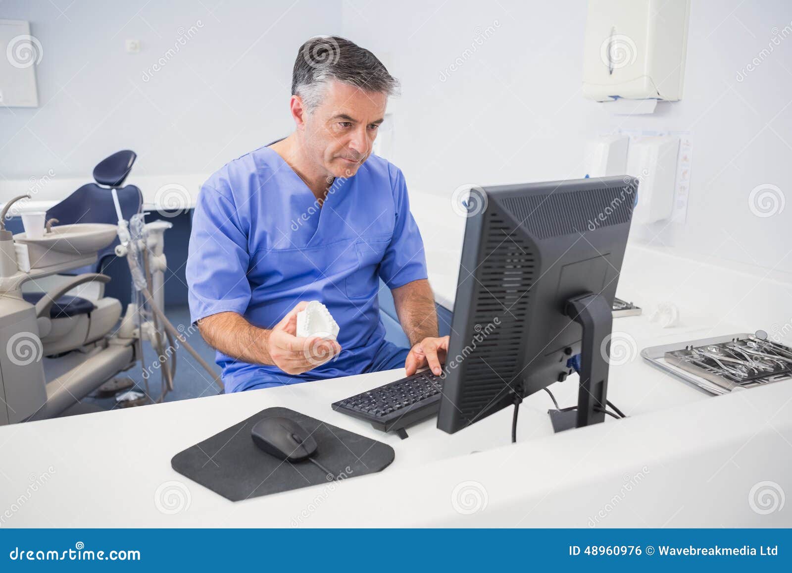 Dentista Serio Che Per Mezzo Del Computer E Tenendo Modello Fotografia ...