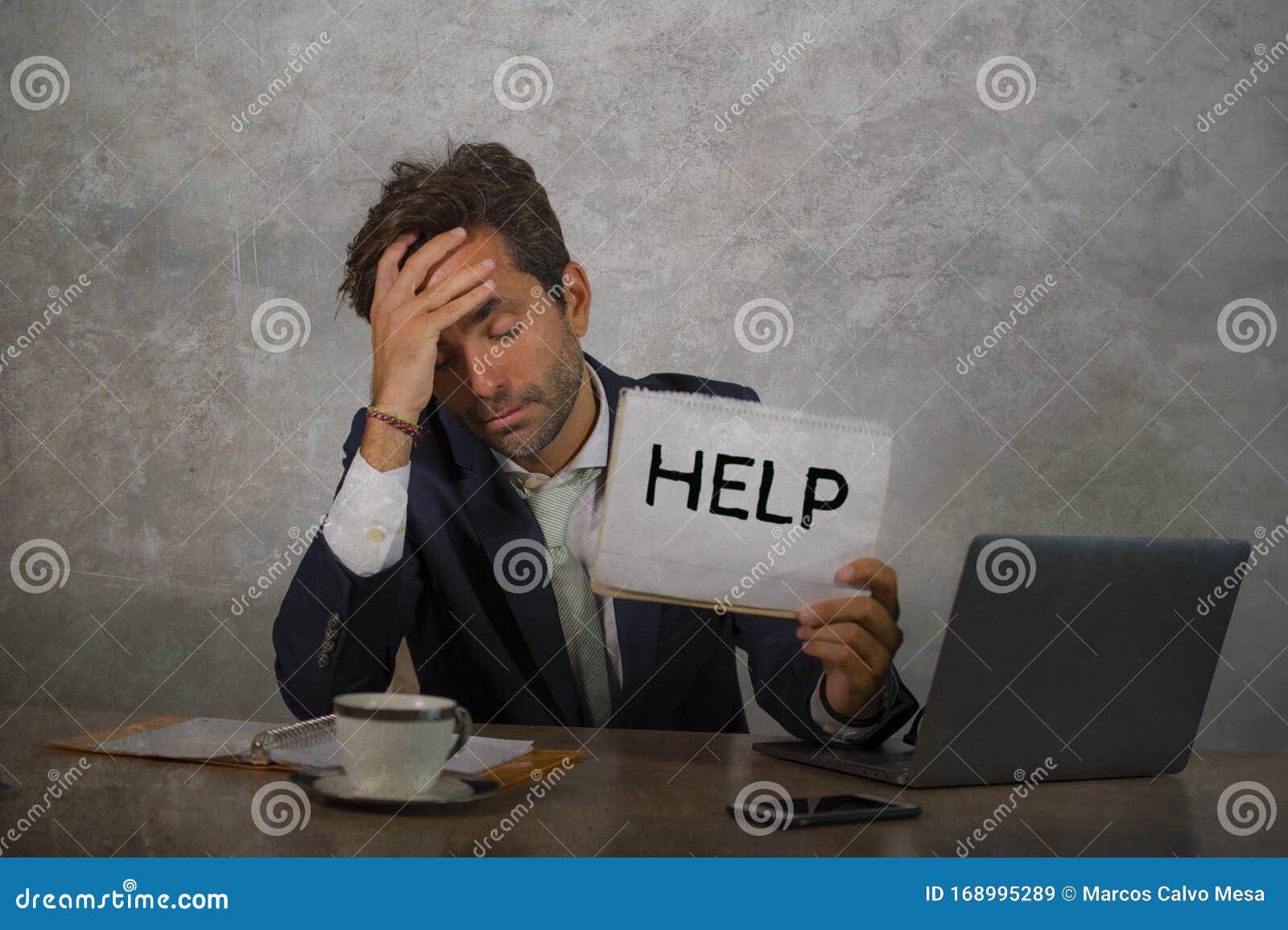 Depressed And Stressed Attractive Hispanic Man In Suit And Tie Working